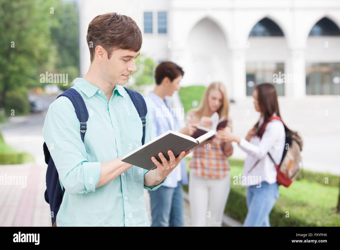 International student in college with backpack reading a book with the ...