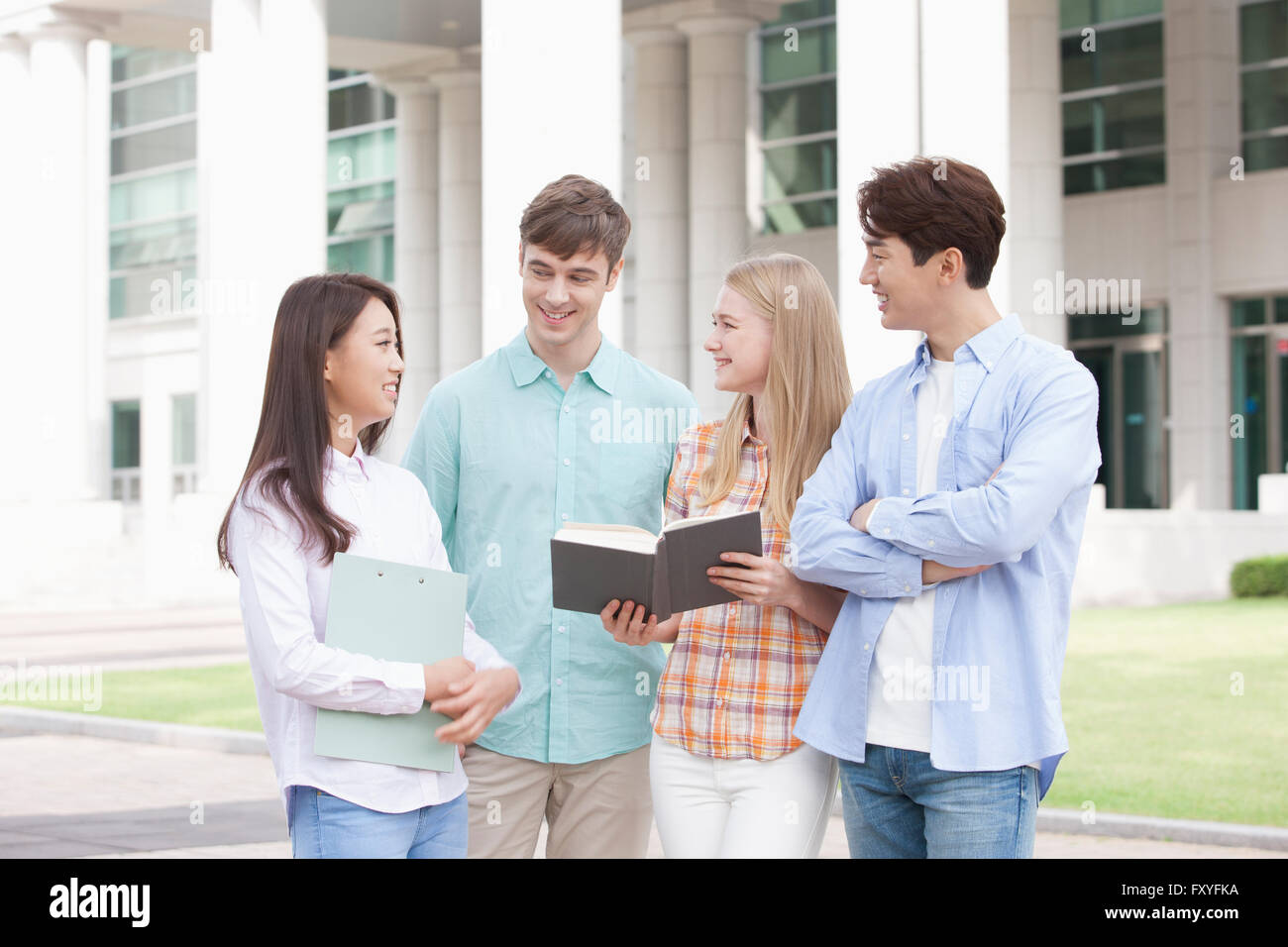 International students and domestic students in college with a book having a conversation ...