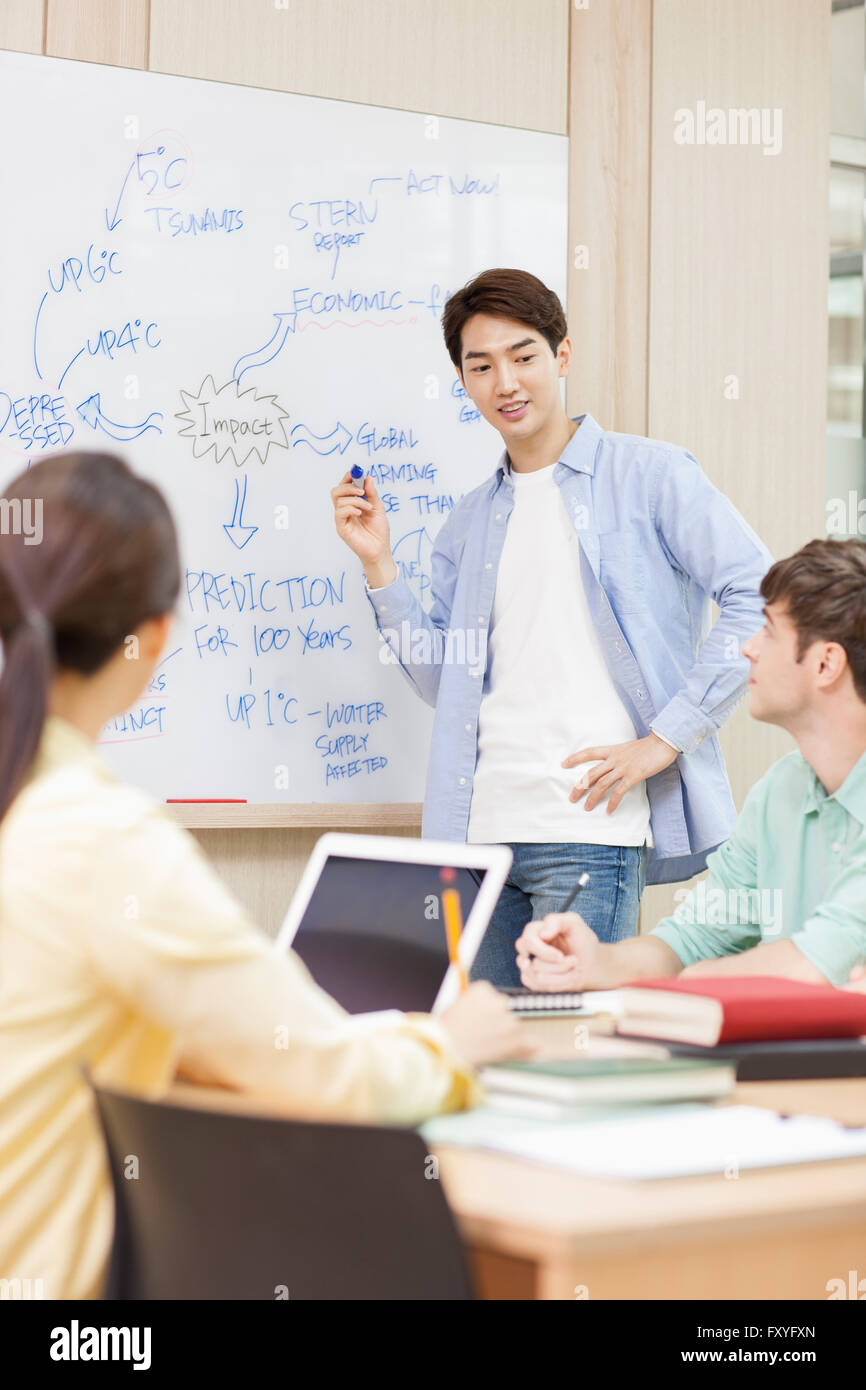 Aisan student in college giving a lecture in front of her friends in ...