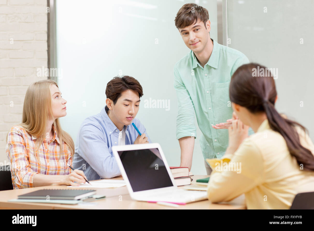 International student standing at the desk with other students sitting ...