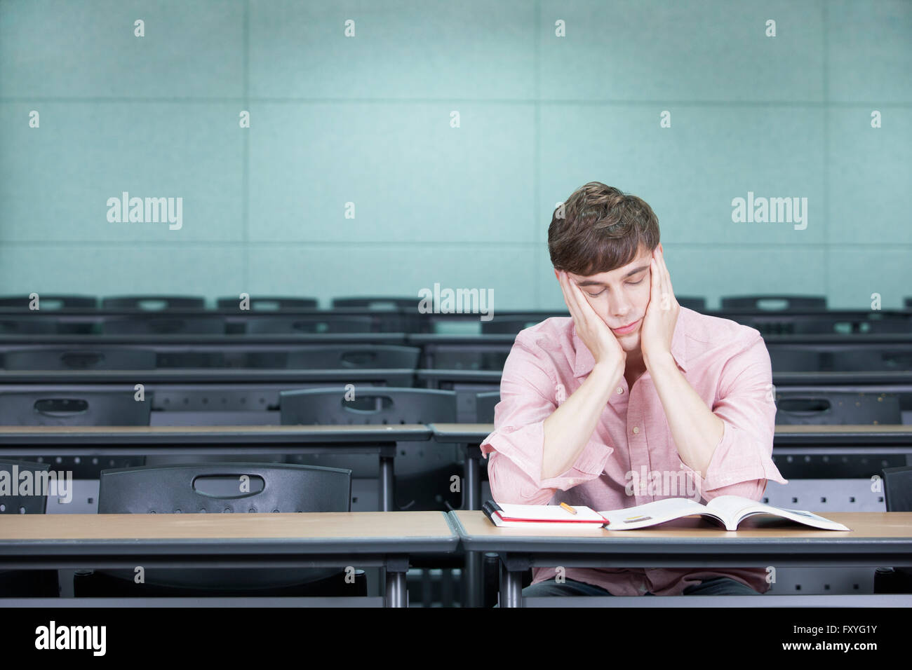 International student in college being stressed seated at desk in a ...