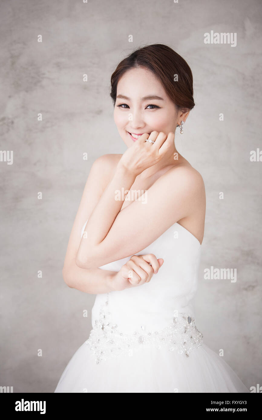 Bride staring forward with a smile with her hand on her mouth to show ...