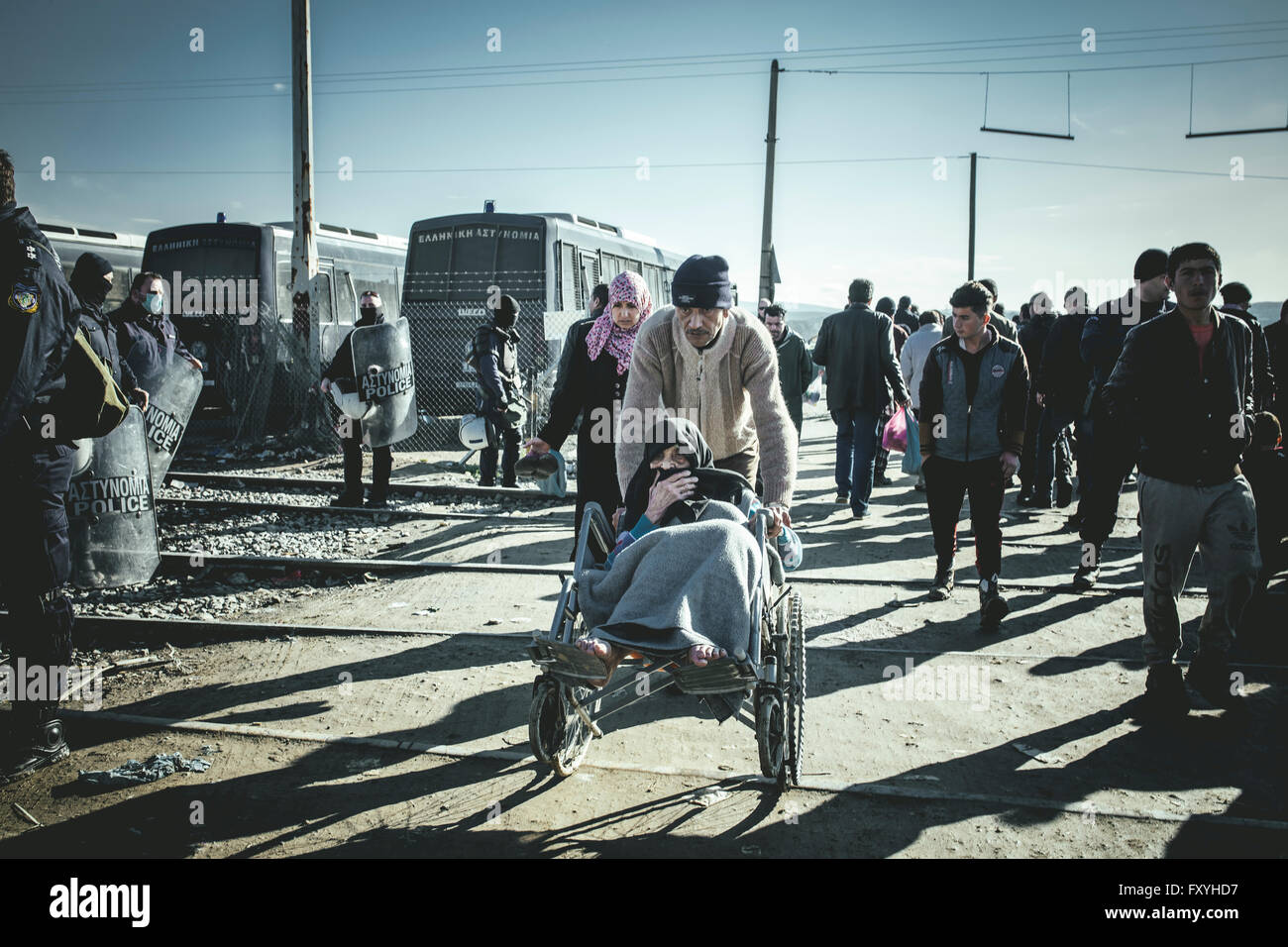 Refugees and old woman in a wheelchair on the border fence, refugee ...