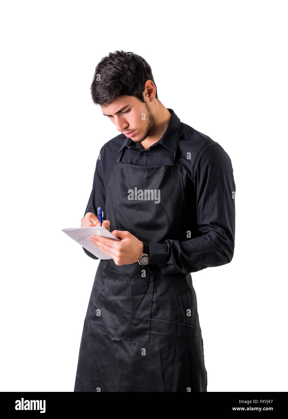 Young chef or waiter posing, wearing black apron and shirt, writing ...