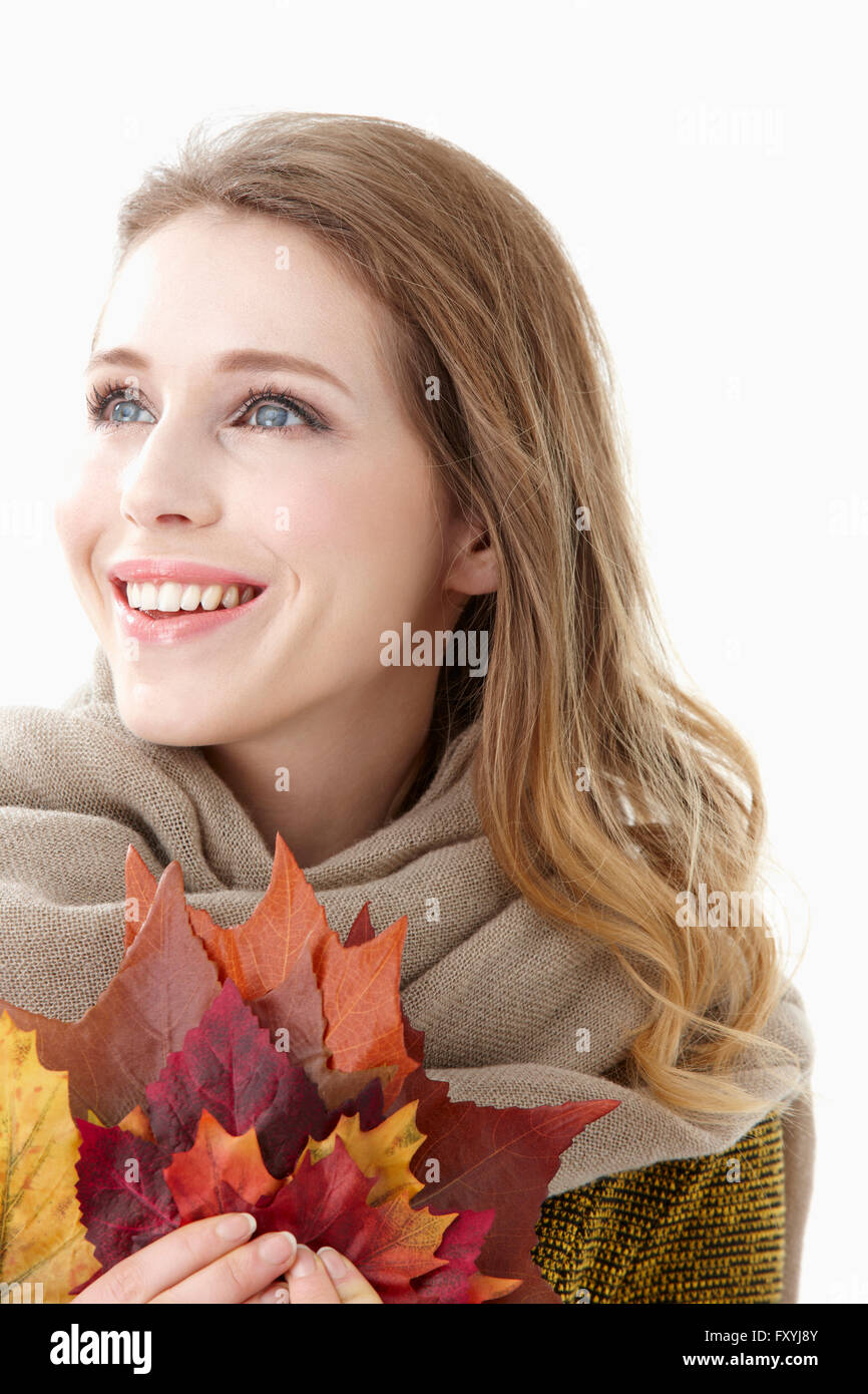 Woman in muffler holding maple leaves looking up representing fall ...