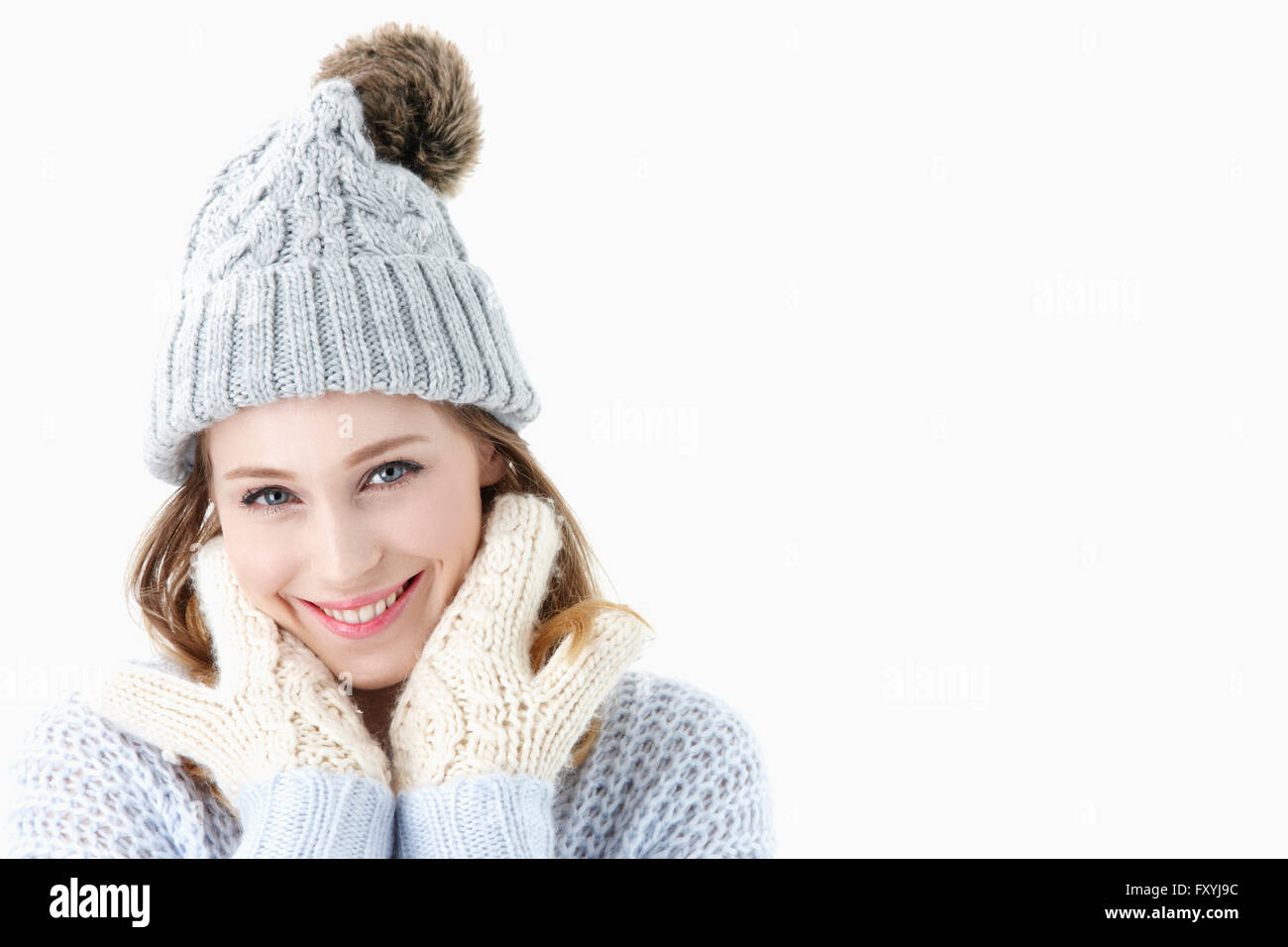 Woman in winter clothes touching her face with a smile Stock Photo - Alamy