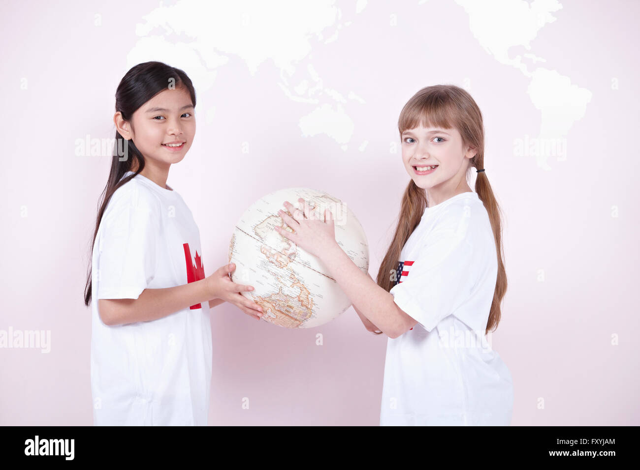 Two girls from different countries holding a globe together Stock Photo ...