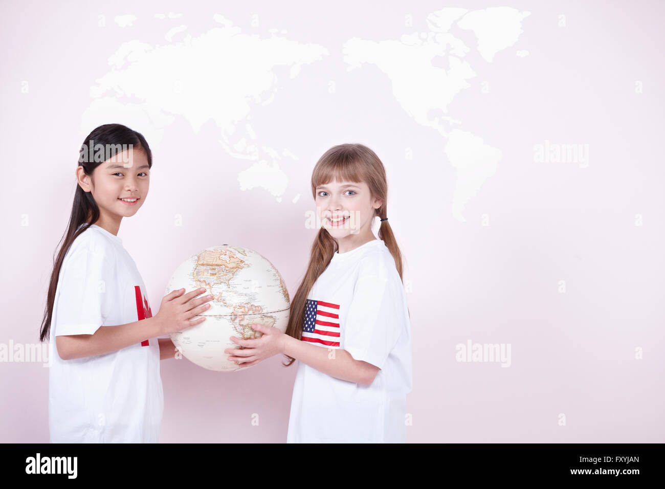 Two girls from different countries holding a globe together Stock Photo ...