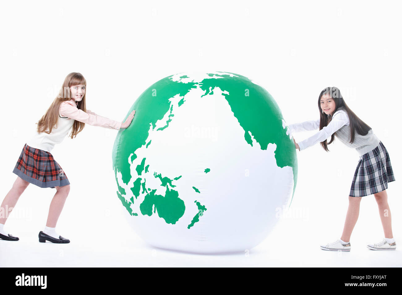 Two middle school girls from different countries pushing a globe ...