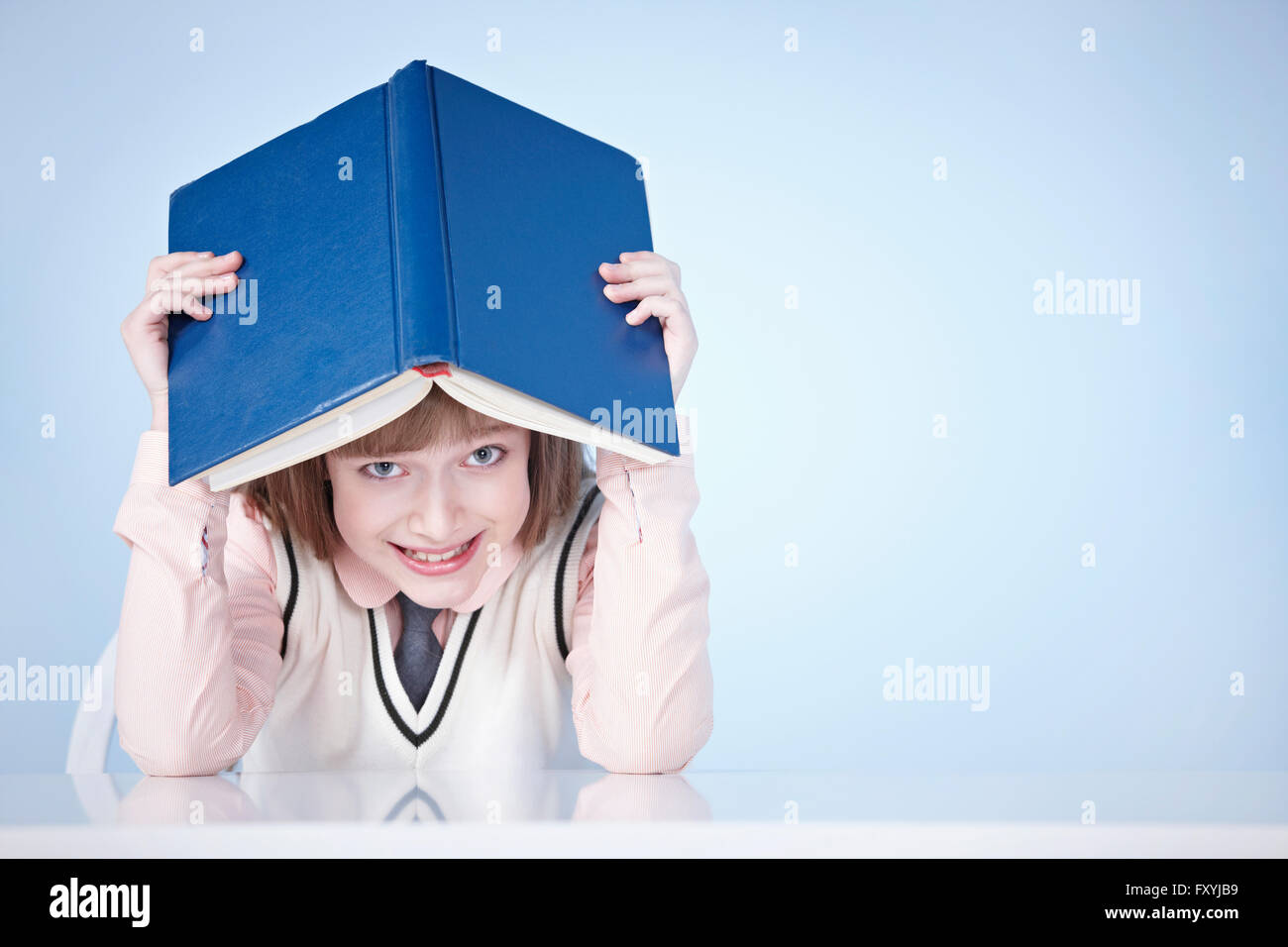 Girl in school uniform holding a book over her head Stock Photo - Alamy