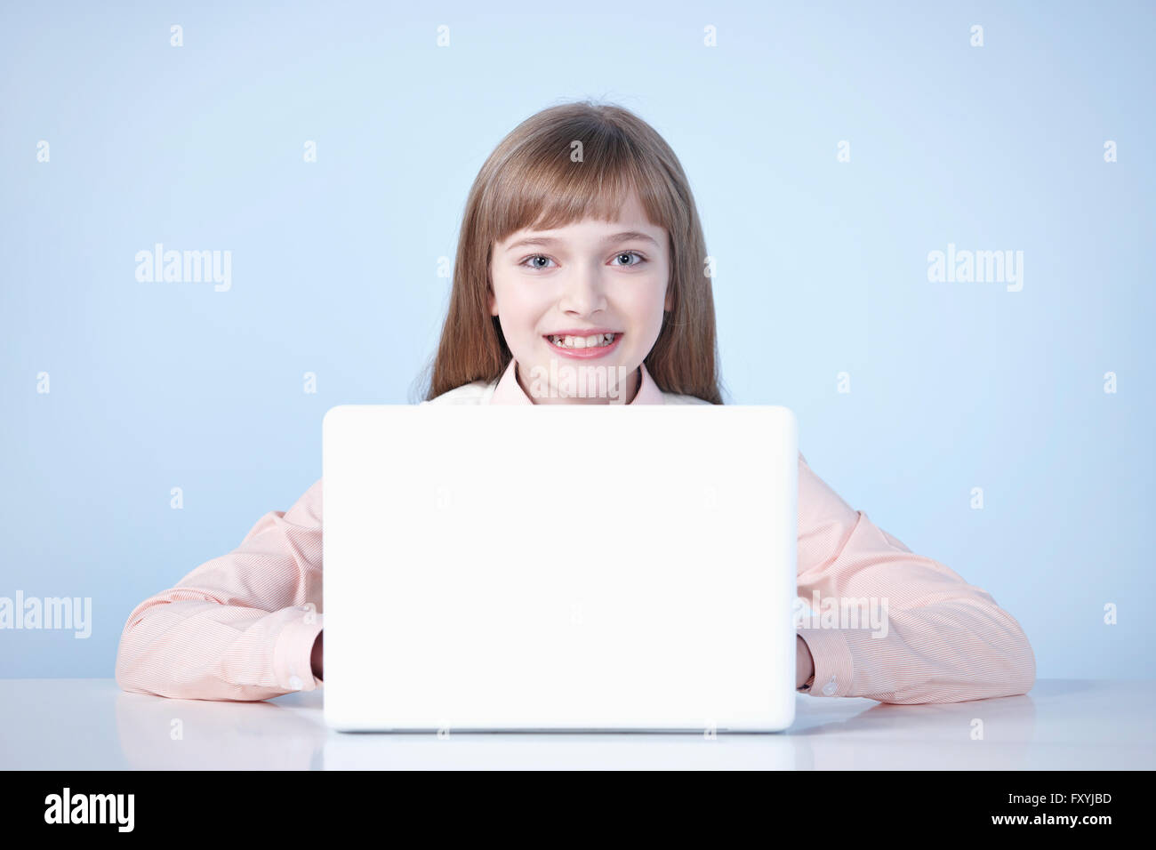 Girl seated at desk with a laptop Stock Photo - Alamy