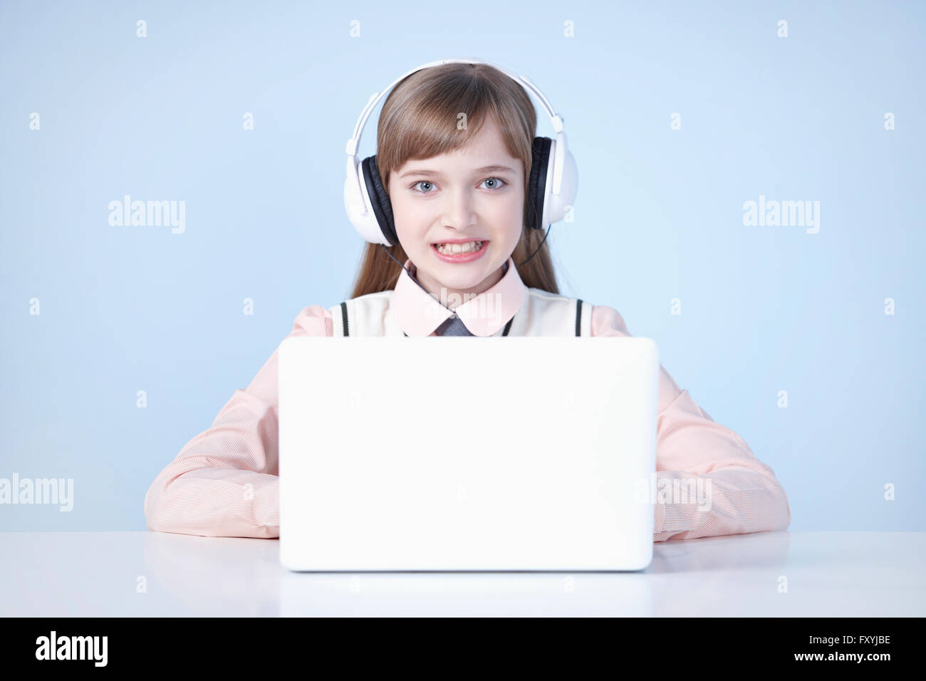Girl seated at desk with a laptop wearing headphones Stock Photo - Alamy