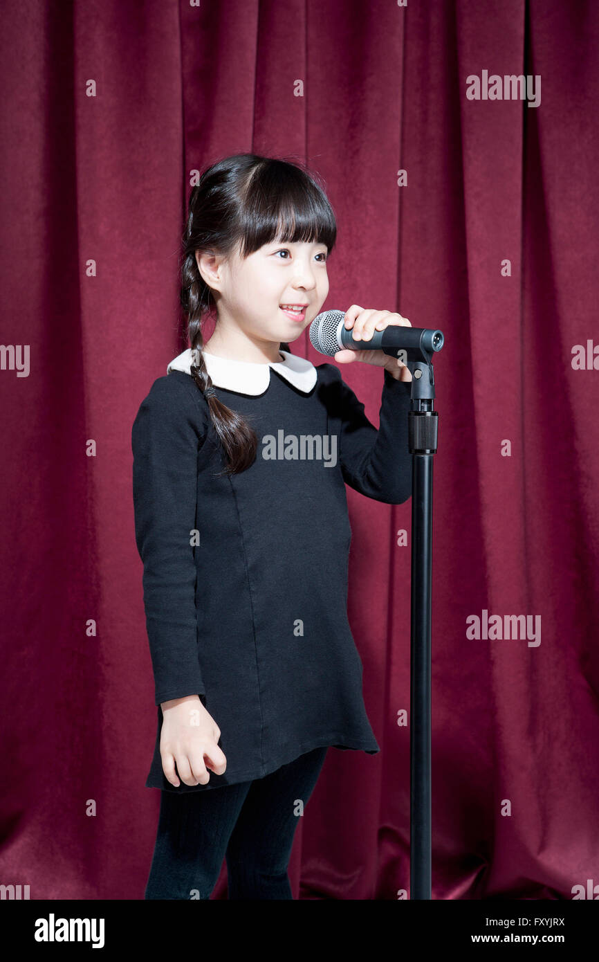 Girl speaking through standing microphone on the stage Stock Photo - Alamy