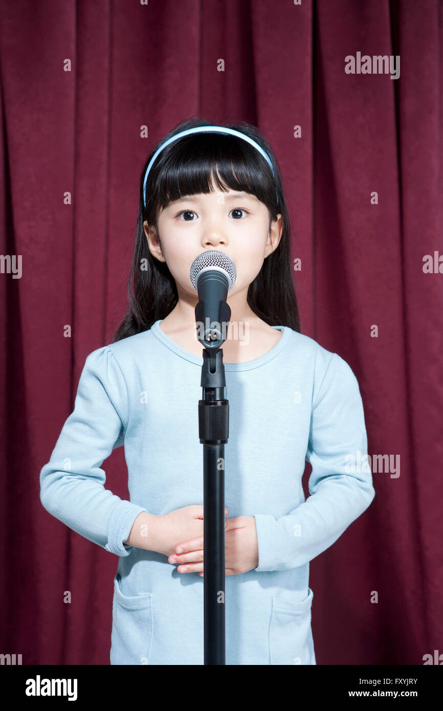 Girl singing behind a standing microphone on the stage Stock Photo - Alamy