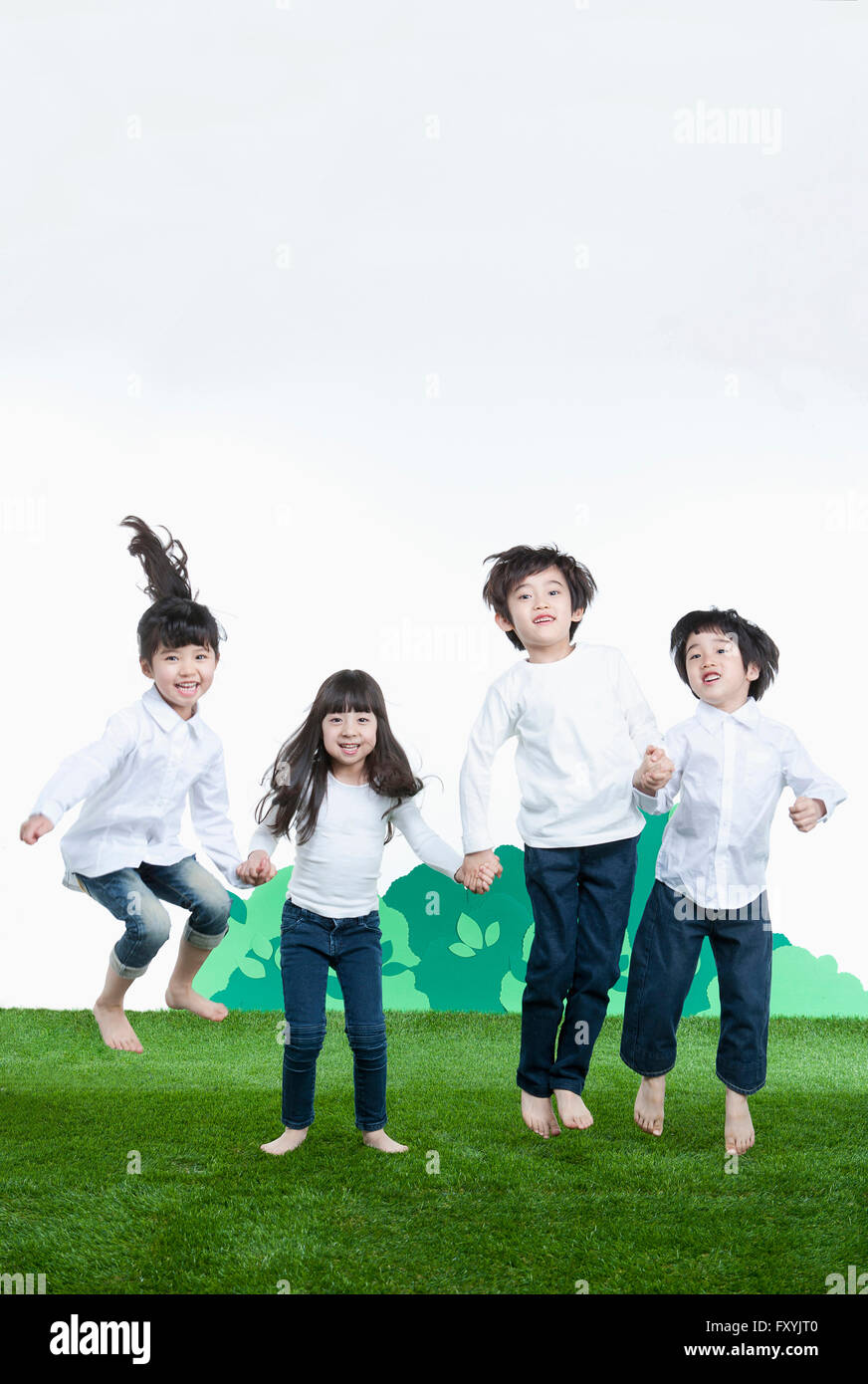 Four children jumping on grass hand in hand Stock Photo - Alamy
