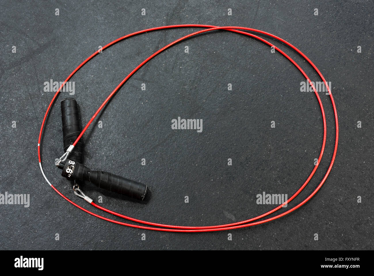 Red jump rope with black handles on a black gym floor Stock Photo - Alamy