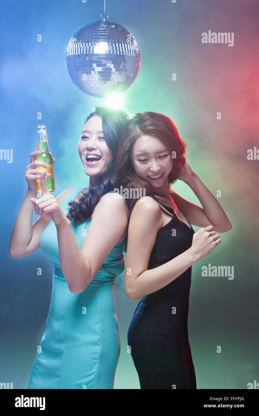 Two smiling women dancing with beer bottle at nightclub Stock Photo - Alamy