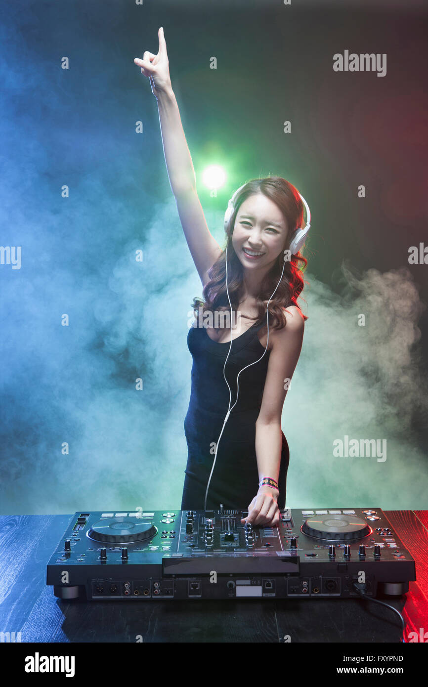 Young smiling female DJ holding her hand staring at front at nightclub ...