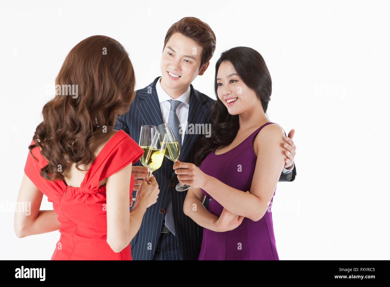 Portrait of three young people toasting at party smiling face to face ...