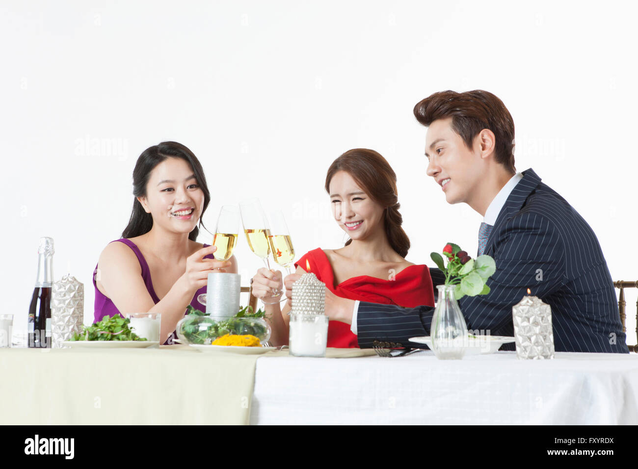 Portrait of three young smiling people toasting during meals at party ...