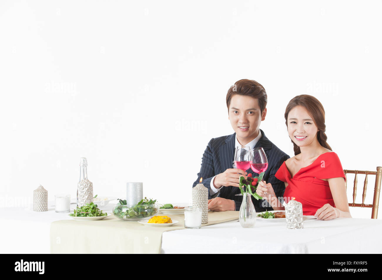 Portrait of young smiling couple toasting at party staring at front ...