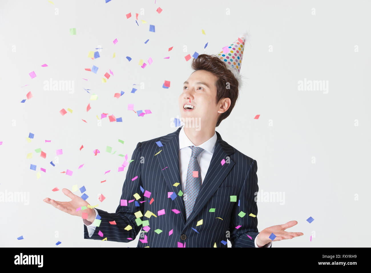 Side view portrait of young smiling man looking up at confetti opening ...