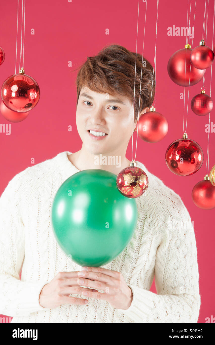 Portrait of young smiling man in his early thirties holding a balloon ...