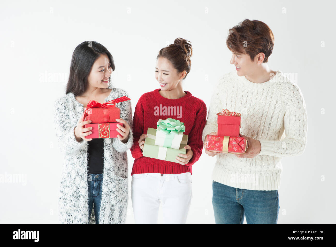 Three young smiling people holding present boxes Stock Photo - Alamy