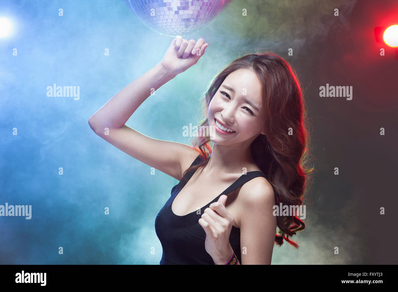 Portrait of young smiling woman dancing staring at front at nightclub ...