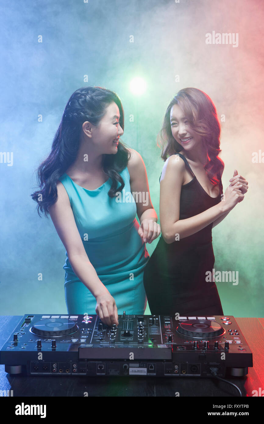 Two young smiling women playing music and dancing face to face at ...