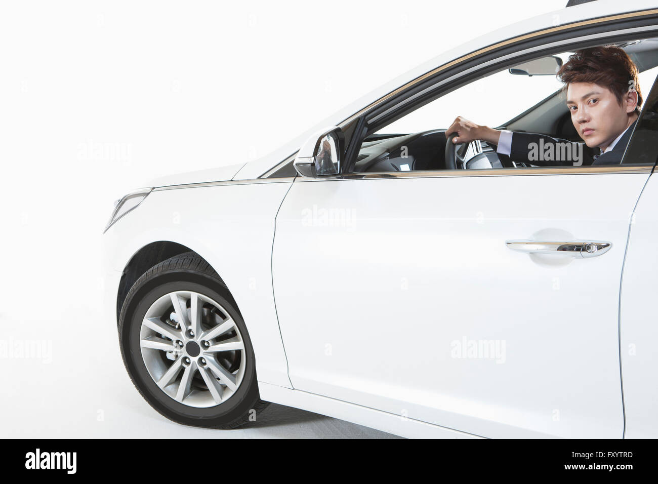 Side view portrait of young man in suit in a car holding handle staring ...