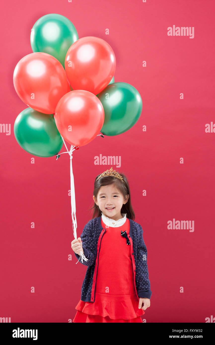 Smiling girl holding balloons staring at front Stock Photo - Alamy