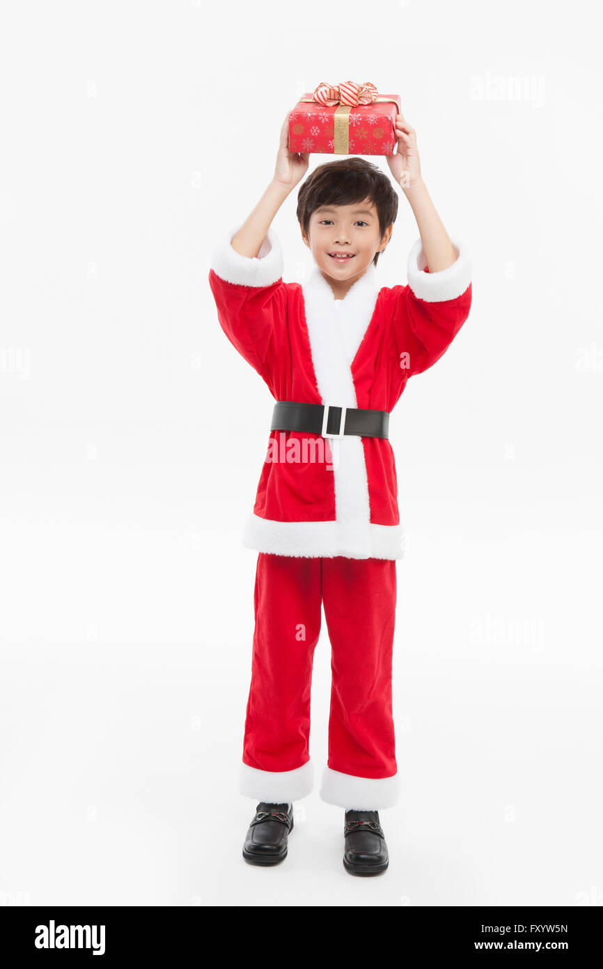 Smiling boy in santa's clothes standing holding a present box over his ...