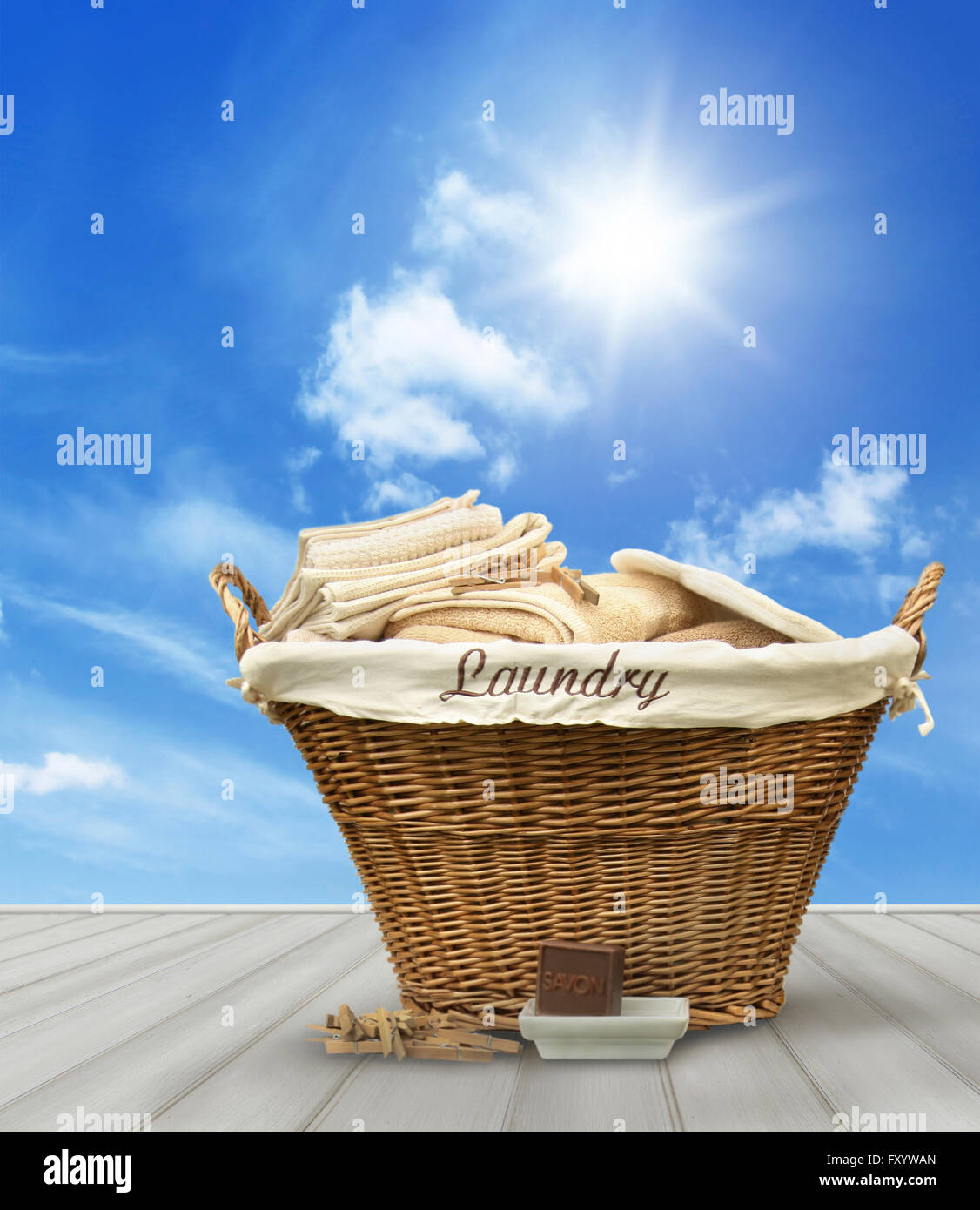 Laundry basket with clothes on rustic table against blue summer sky ...