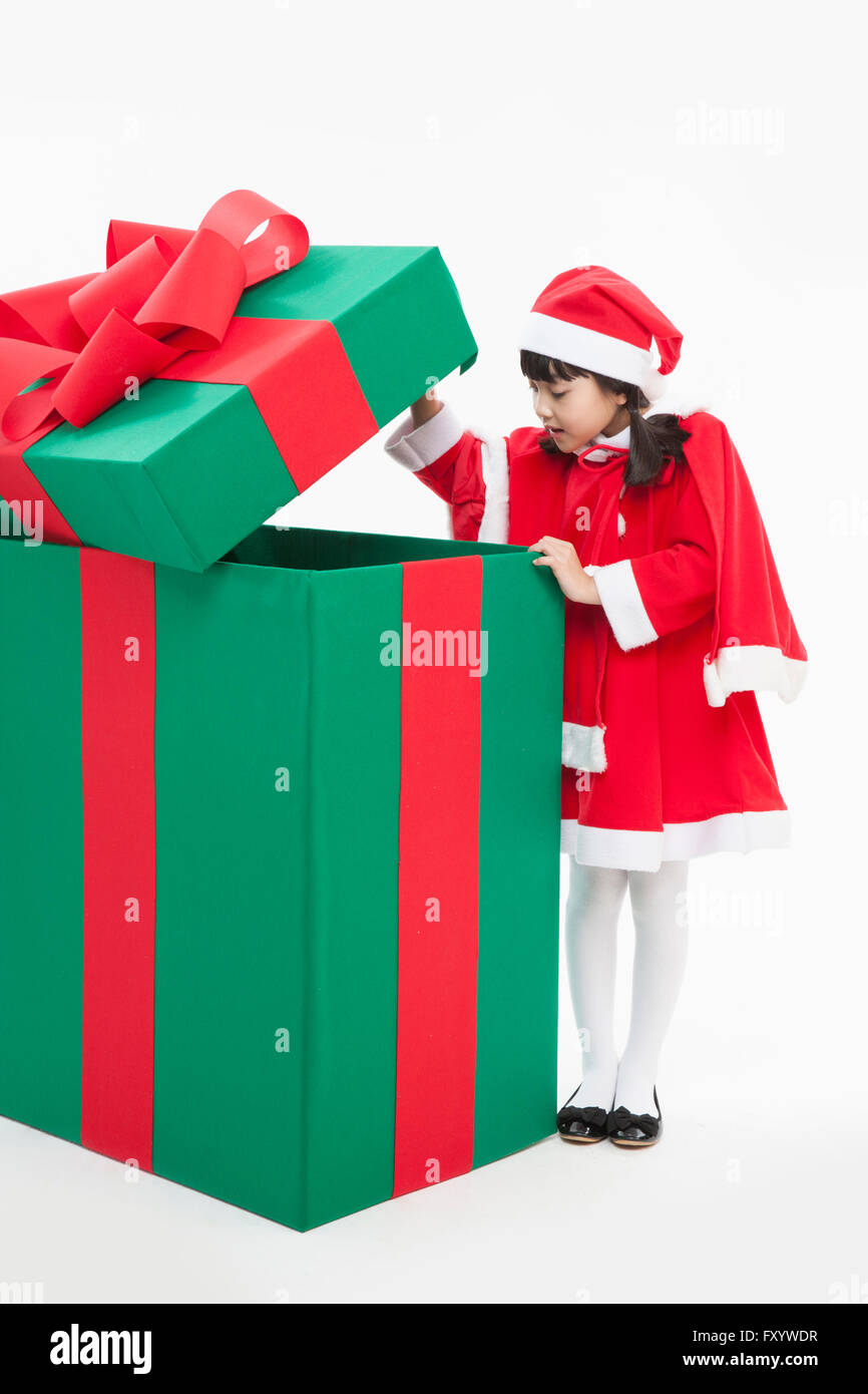 Side view of girl in santa's clothes standing and looking in a big ...