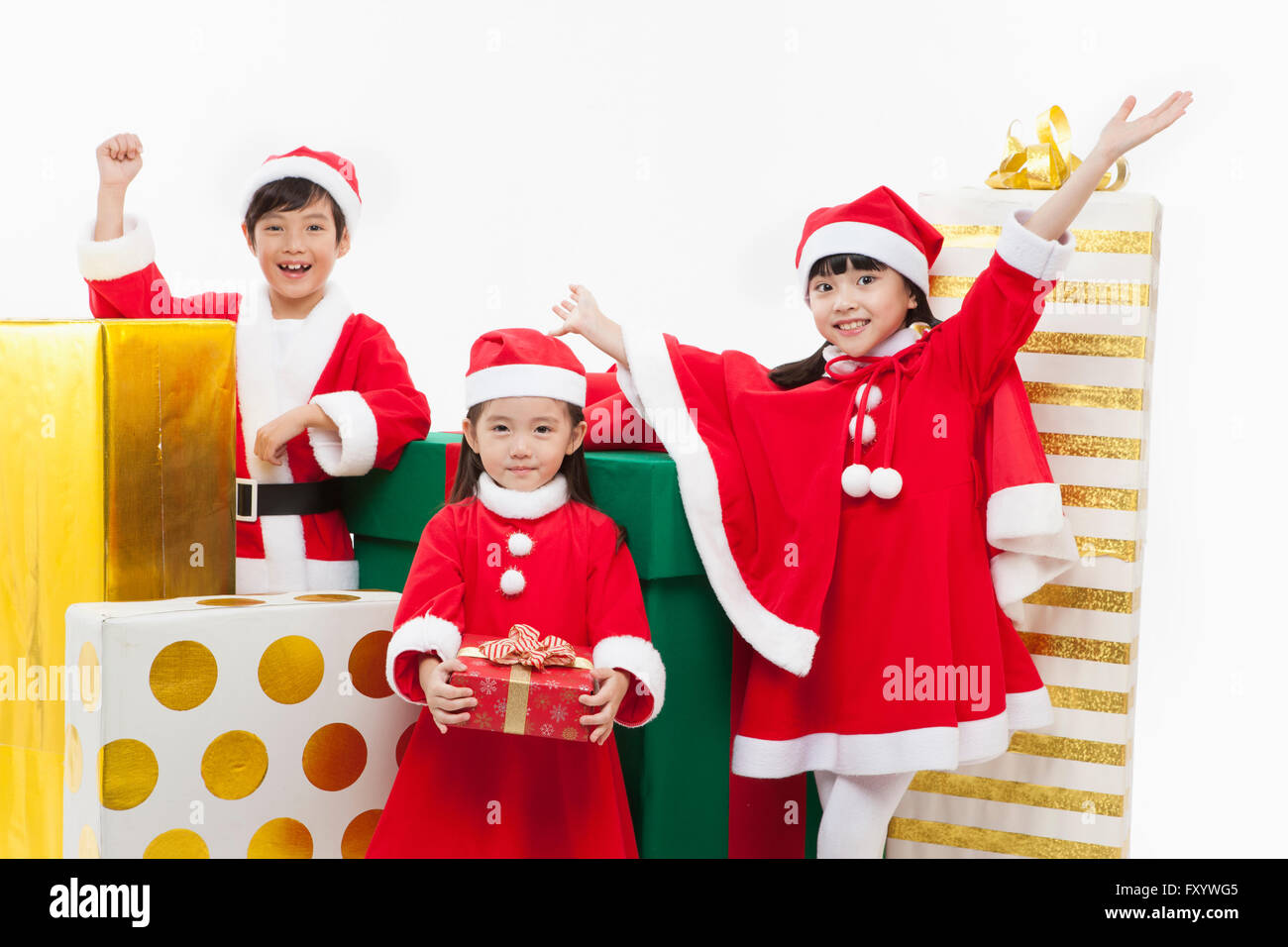Three smiling children in santa's clothes delighted with present boxes ...