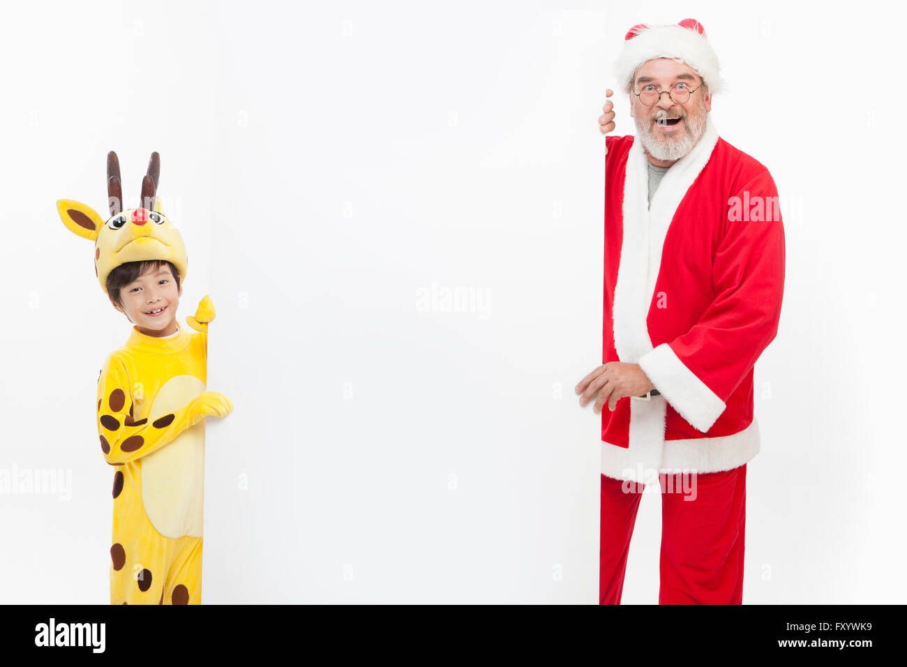 Smiling boy dressed like a reindeer and smiling Santa holding a board ...