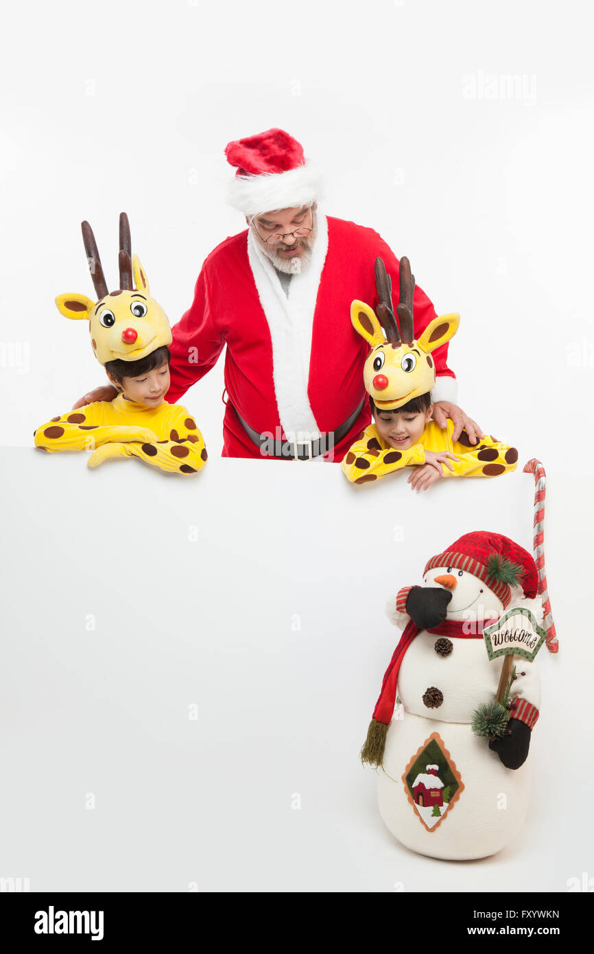 Portrait of boy and girl dressed like reindeer and Santa looking down ...