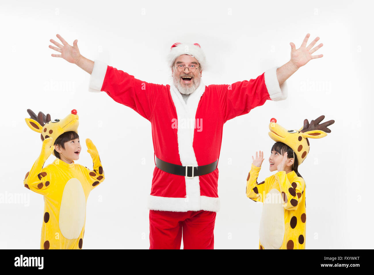 Smiling Santa raising hands staring at front with smiling boy and girl ...