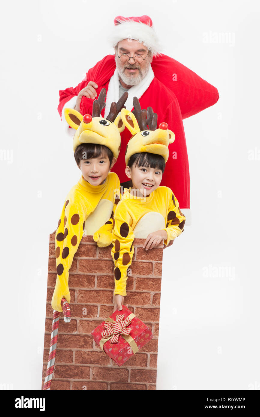 Portrait of smiling children dressed like reindeer holding presents ...
