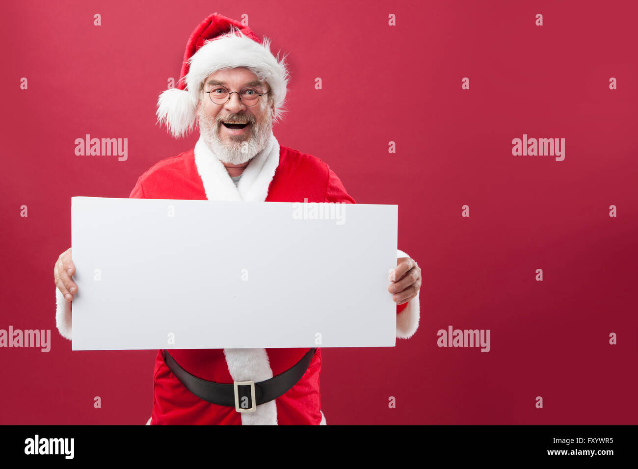 Portrait of smiling Santa showing a paper staring at front Stock Photo ...