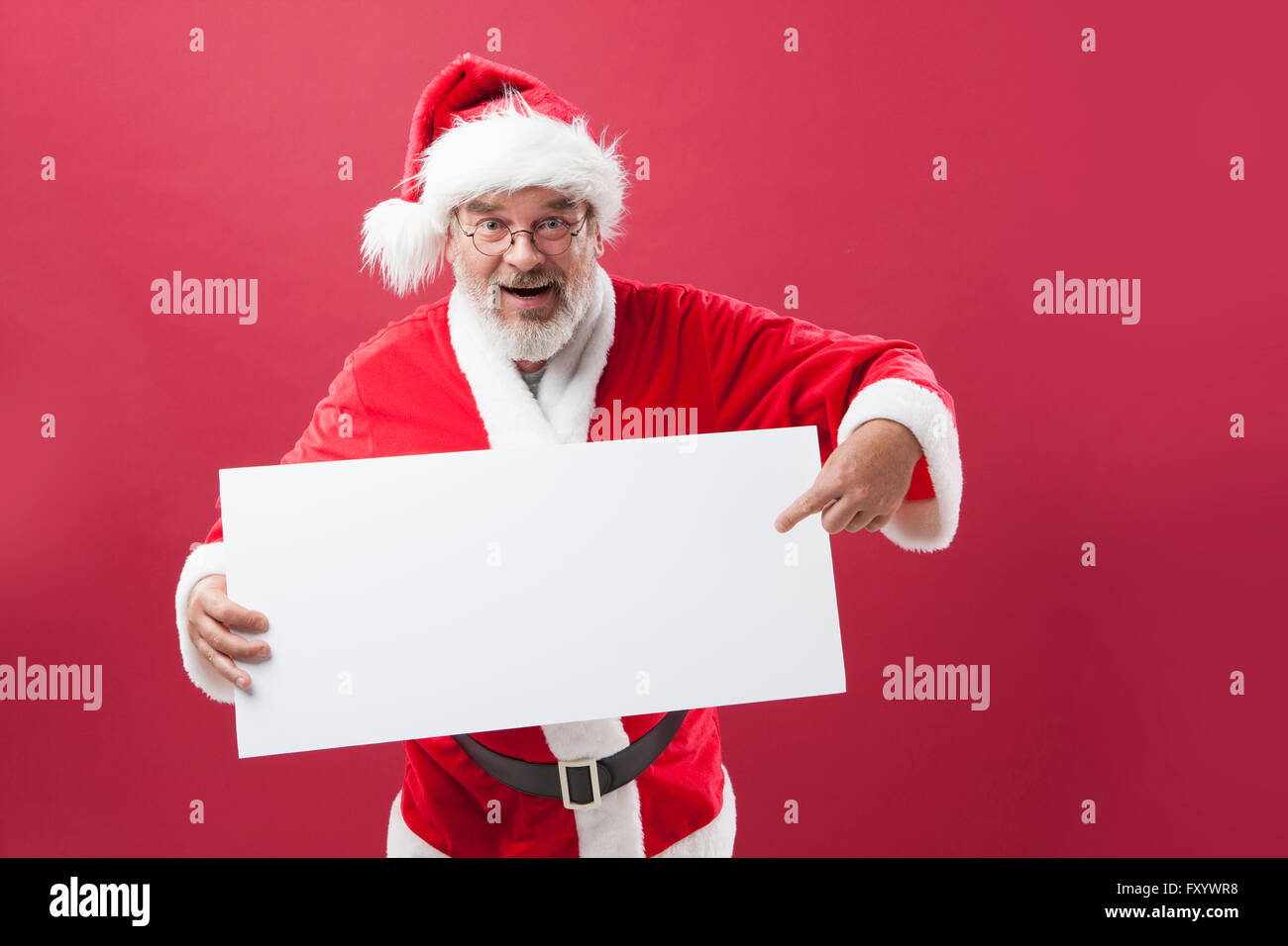 Portrait of smiling Santa holding and pointing to paper staring at ...