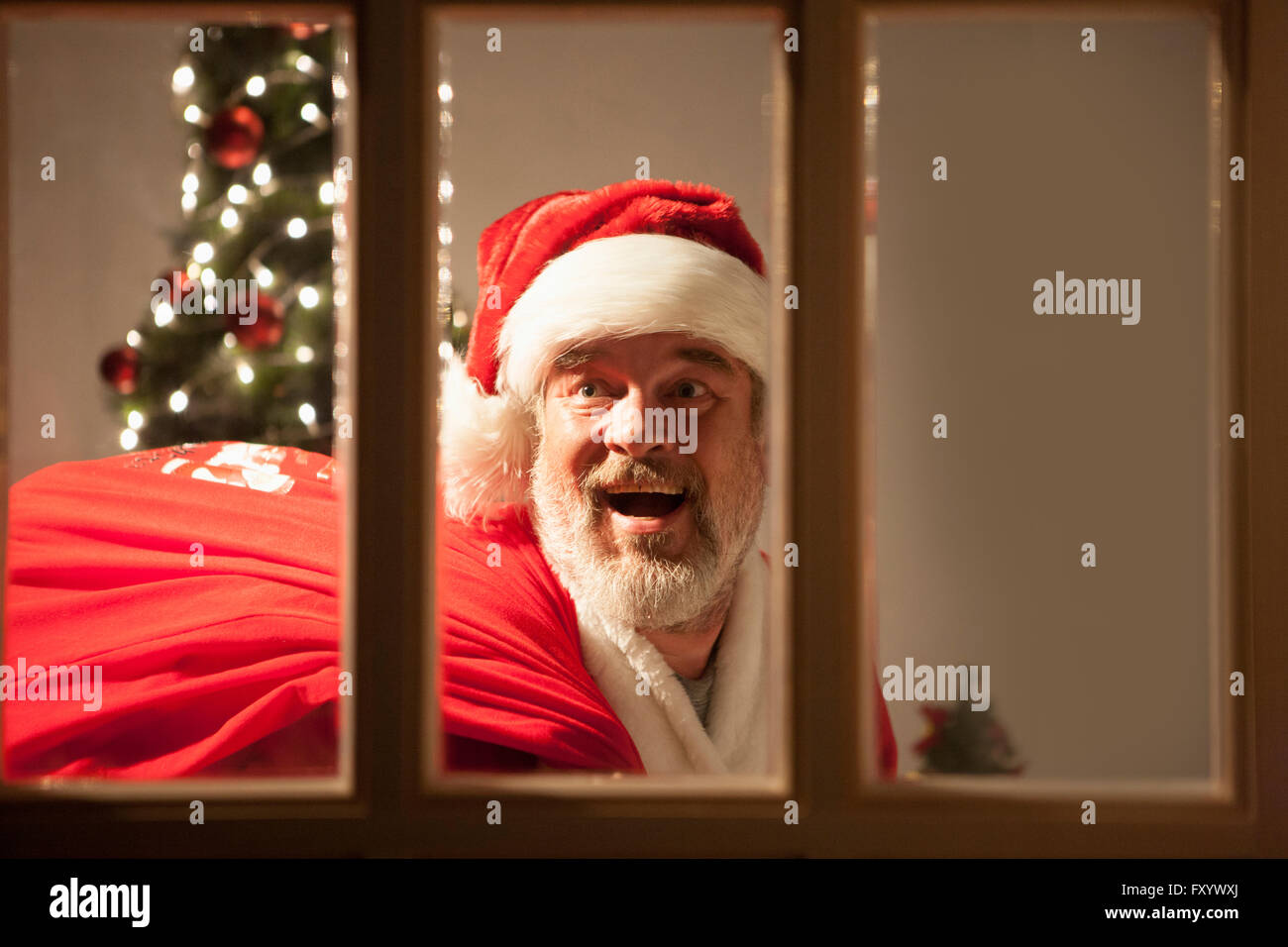 Portrait of smiling Santa looking out of window Stock Photo - Alamy