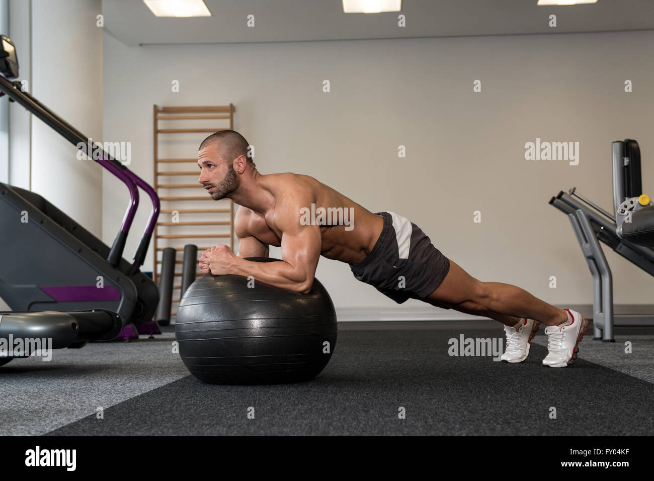 Young Man Exercising Abs On Ball Workout Posture In Fitness Club Stock ...