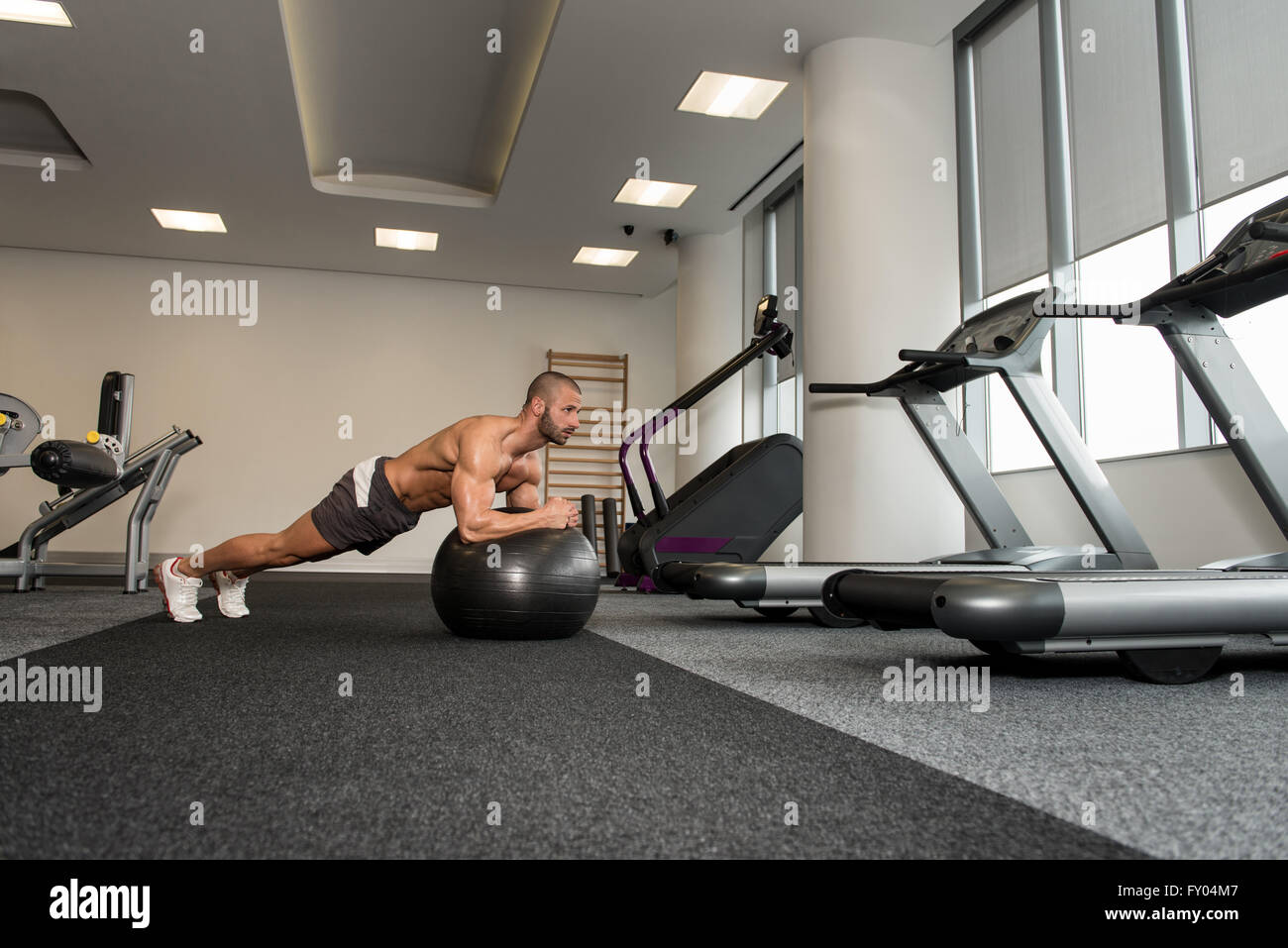Young Man Exercising Abs On Ball Workout Posture In Fitness Club Stock ...