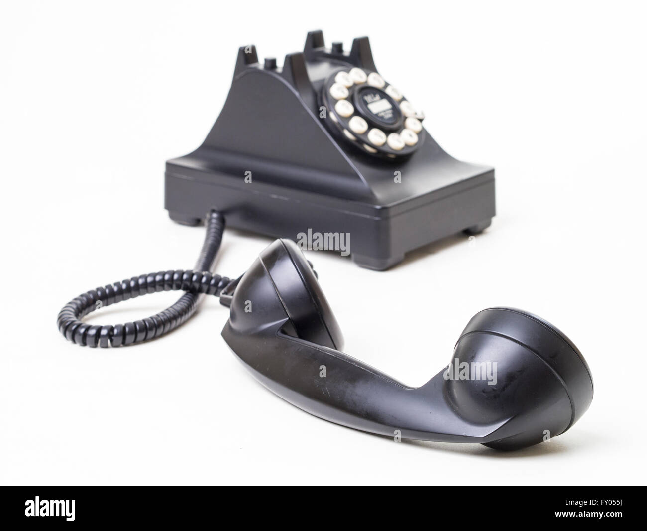 A vintage corded telephone over a white background. Receiver off the ...