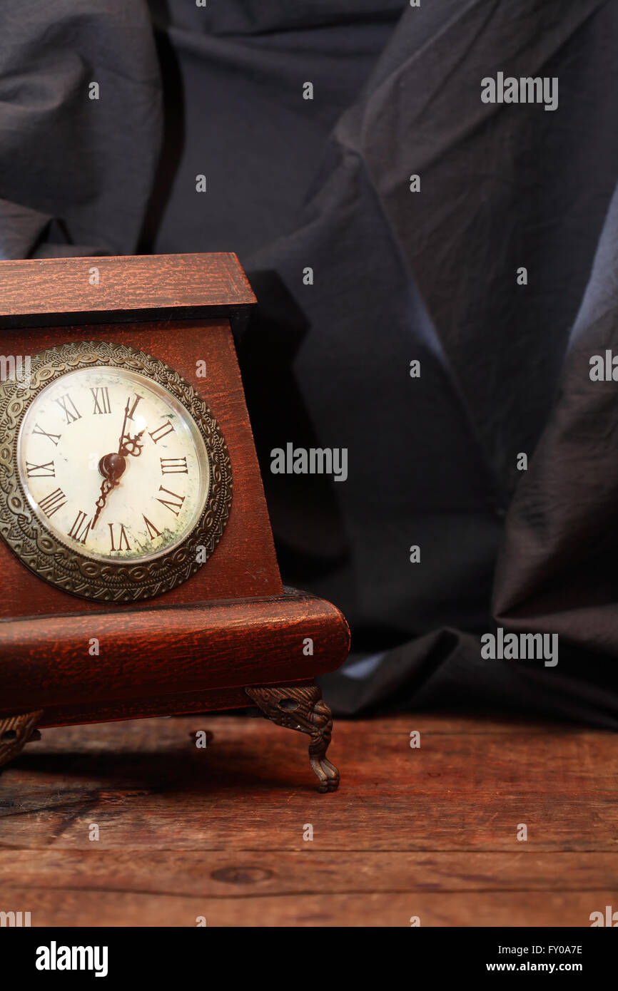 Still life with old vintage table clock on wooden board against dark ...