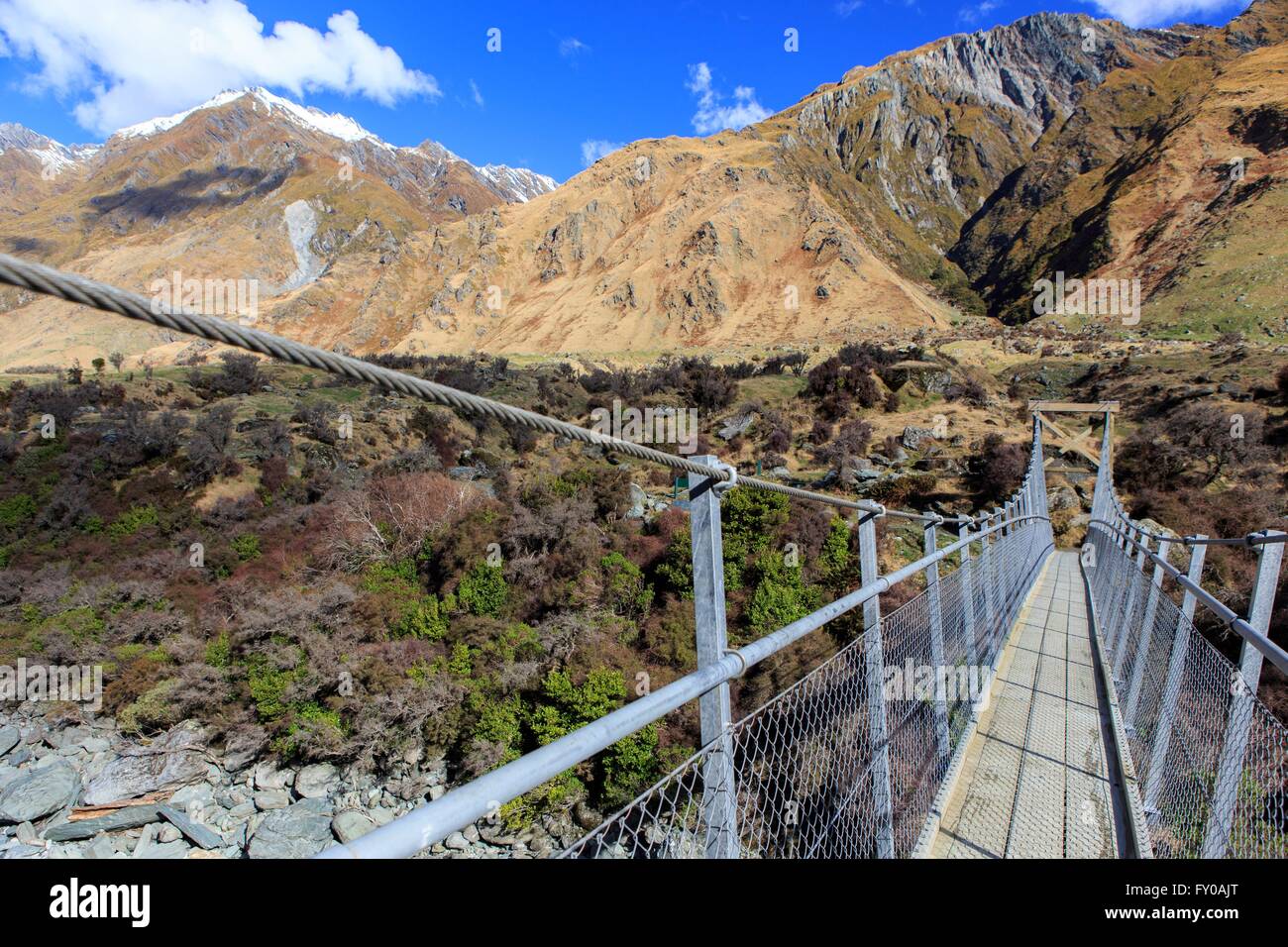 A long suspension bridge over a river on the Fox Glacier track, Wanaka ...