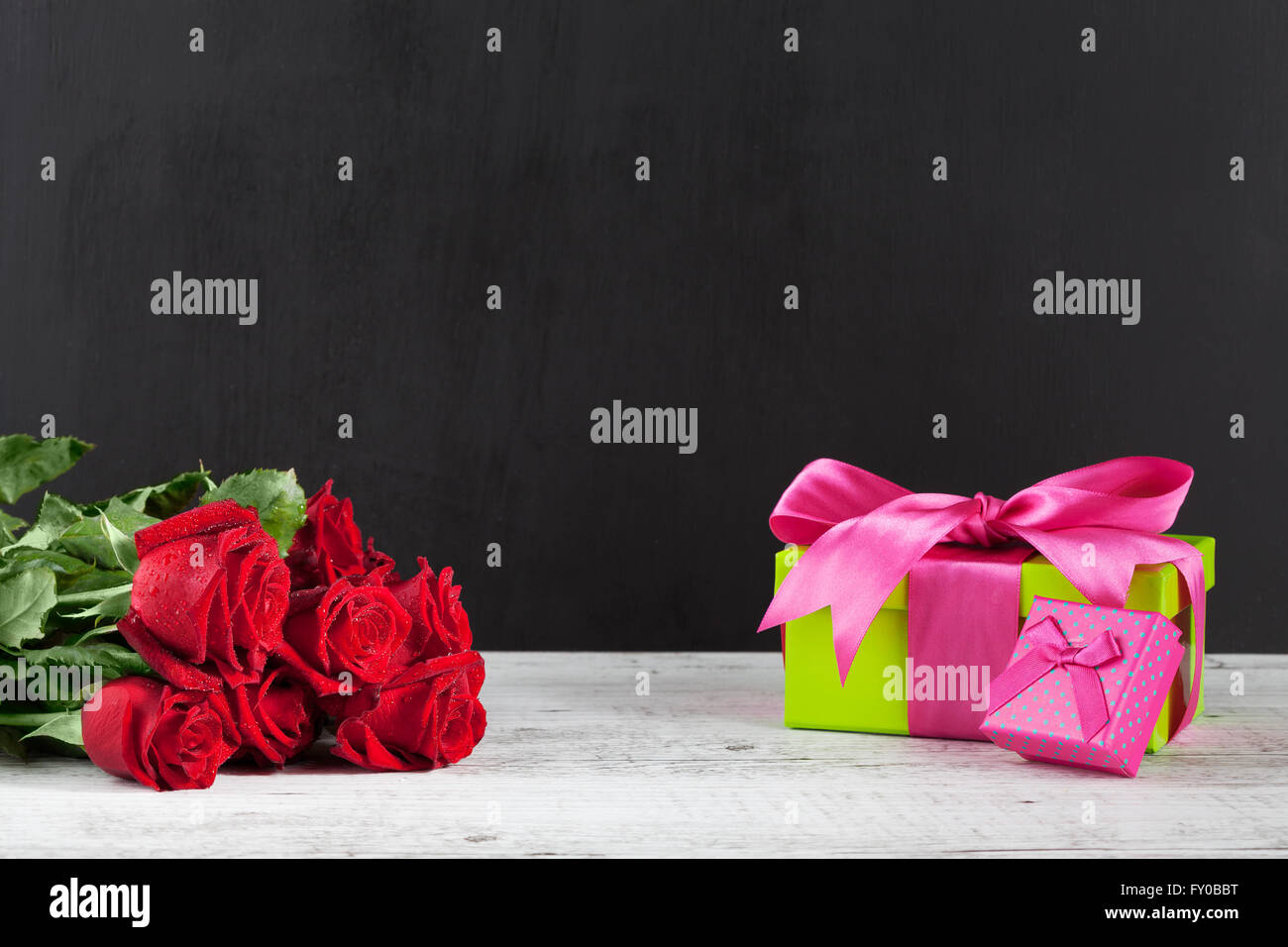 Bunch of red roses with gift boxes on white rustic wooden table. Black ...