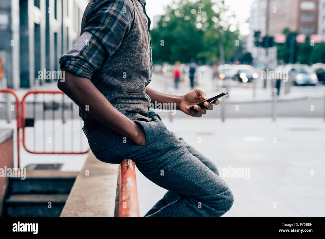 From the neck down view of young afro black man holding a smart phone ...